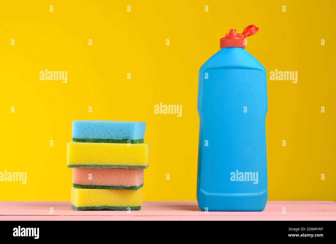 A bottle of dish washing, sponges, on a wooden pastel color table ...
