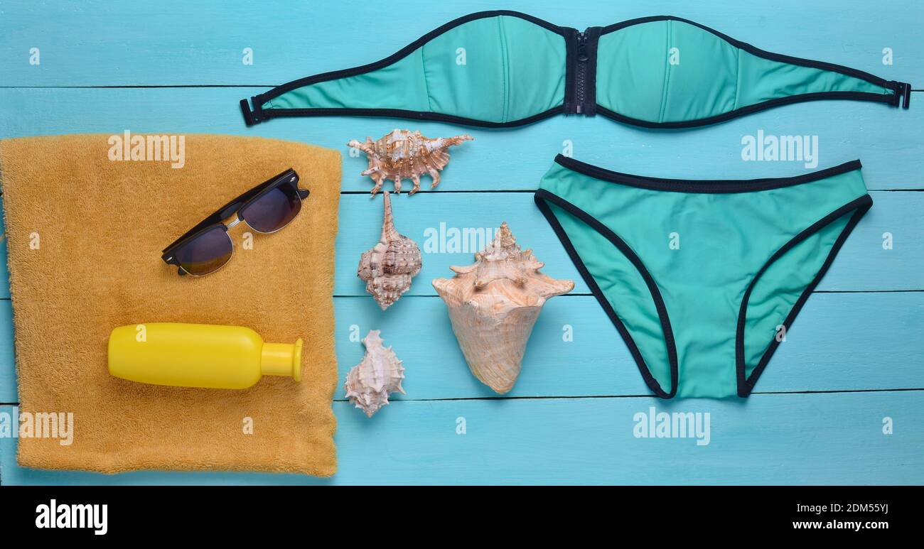 Swimsuit, towel, sunscreen, seashells, sunglasses on blue wooden boards ...
