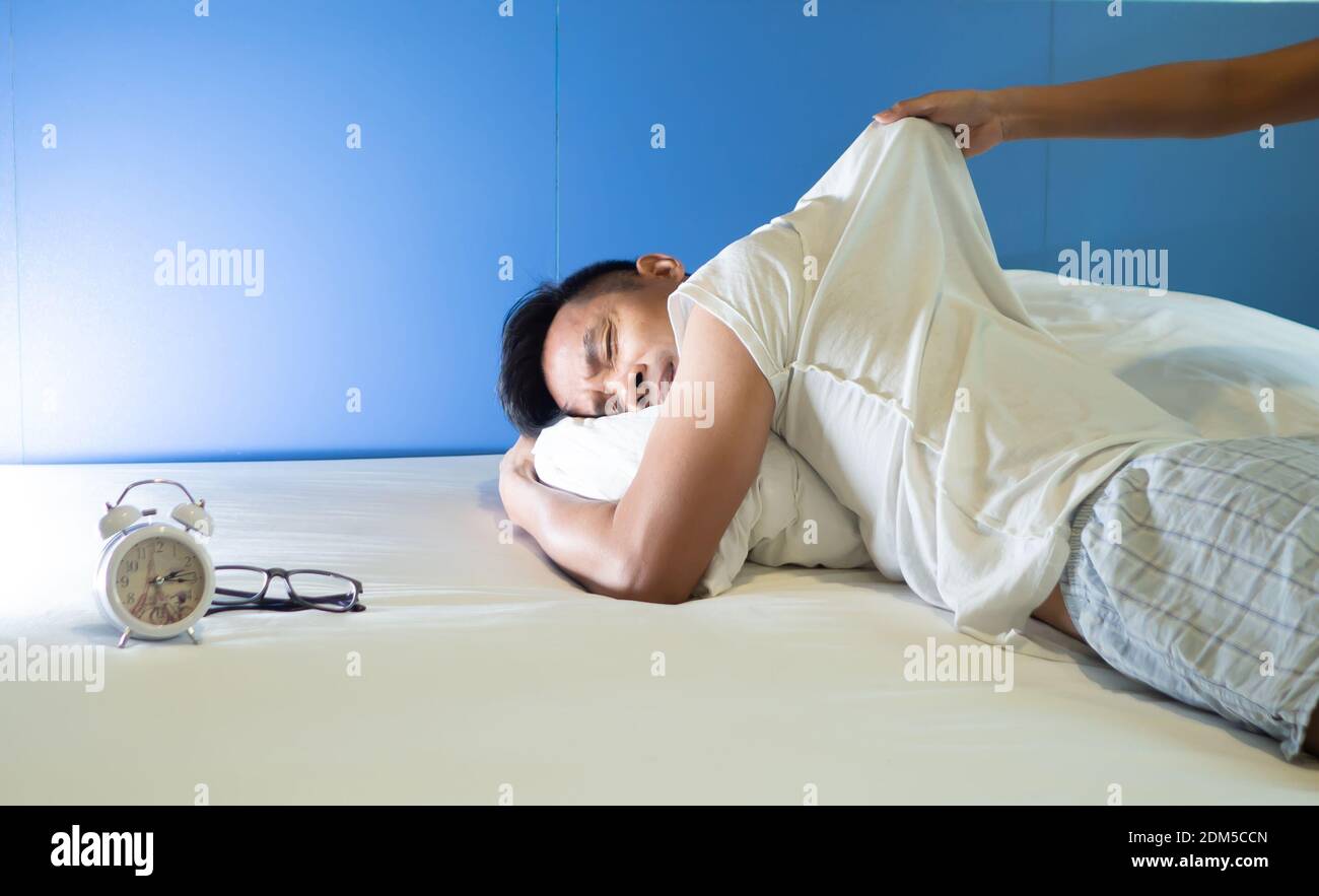 Cropped Hand Of Friend Waking Up Man Sleeping On Bed Against Wall At ...