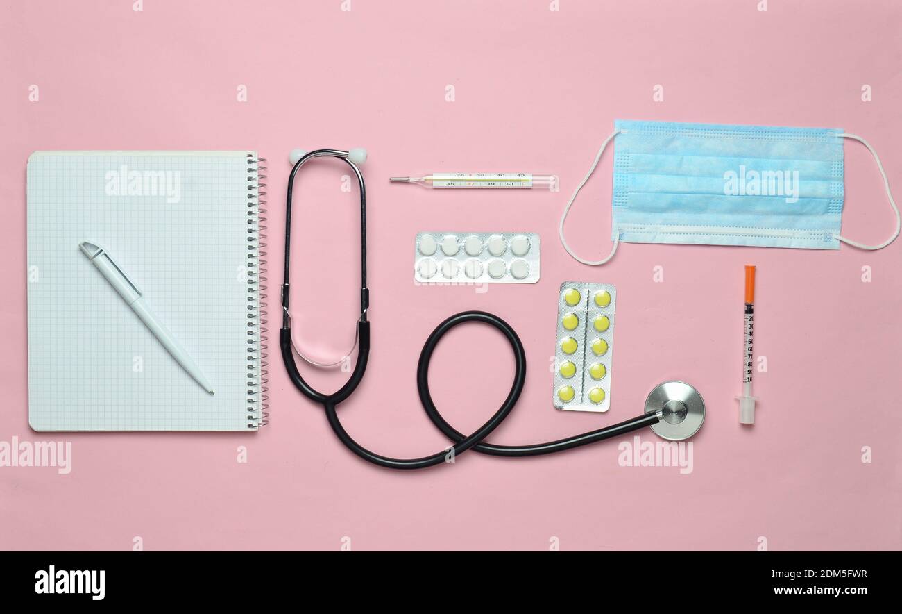 Medical equipment on a pink pastel background. Blisters pills, notepad ...
