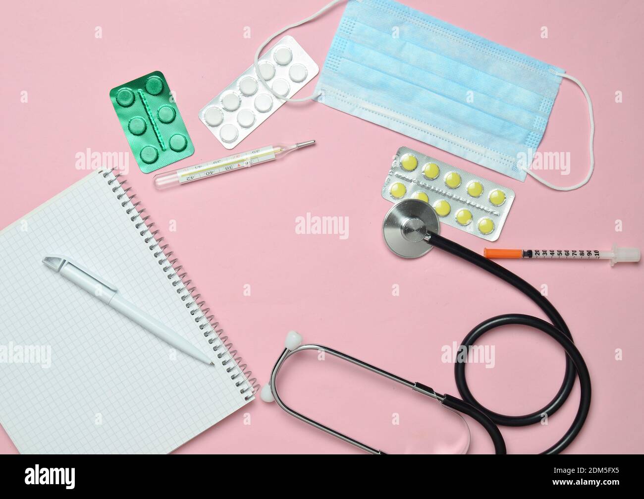 Medical equipment on a pink pastel background. Blisters pills, notepad ...