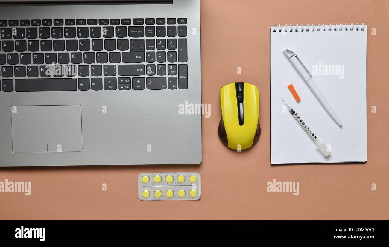 Workplace of a modern doctor. Laptop, wireless mouse, notebook, pills ...