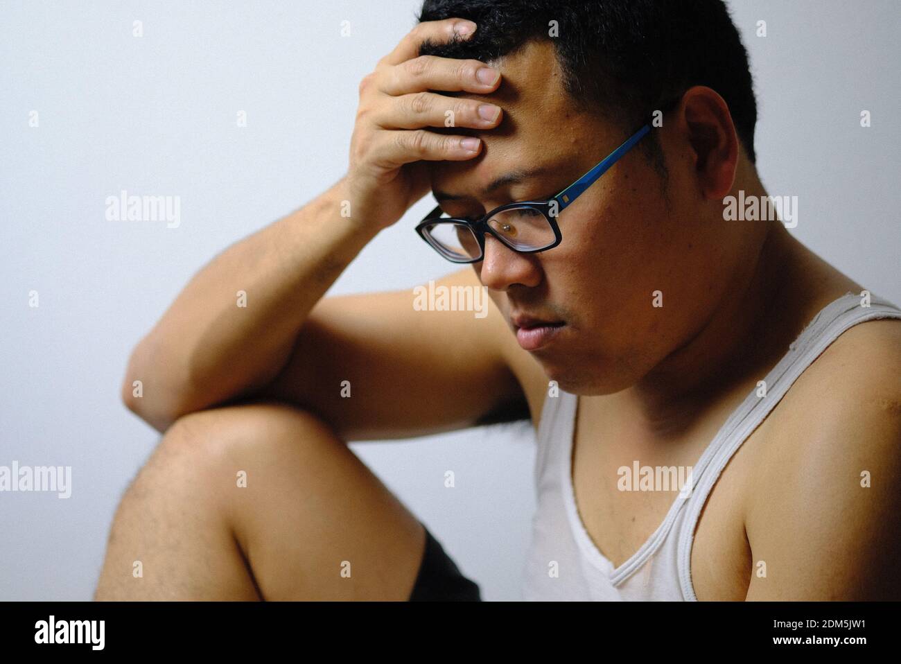 Side View Of Tensed Man With Head In Hand Sitting Against White ...