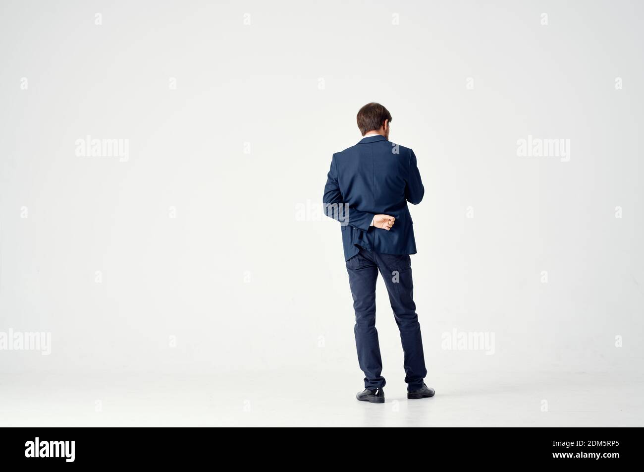 rear view of a man in a suit on a light background gesturing with his ...