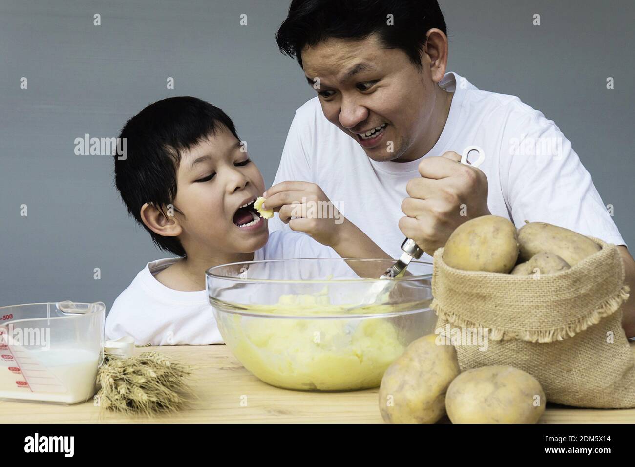 Father And Son Smashing Potatoes In Kitchen Stock Photo - Alamy