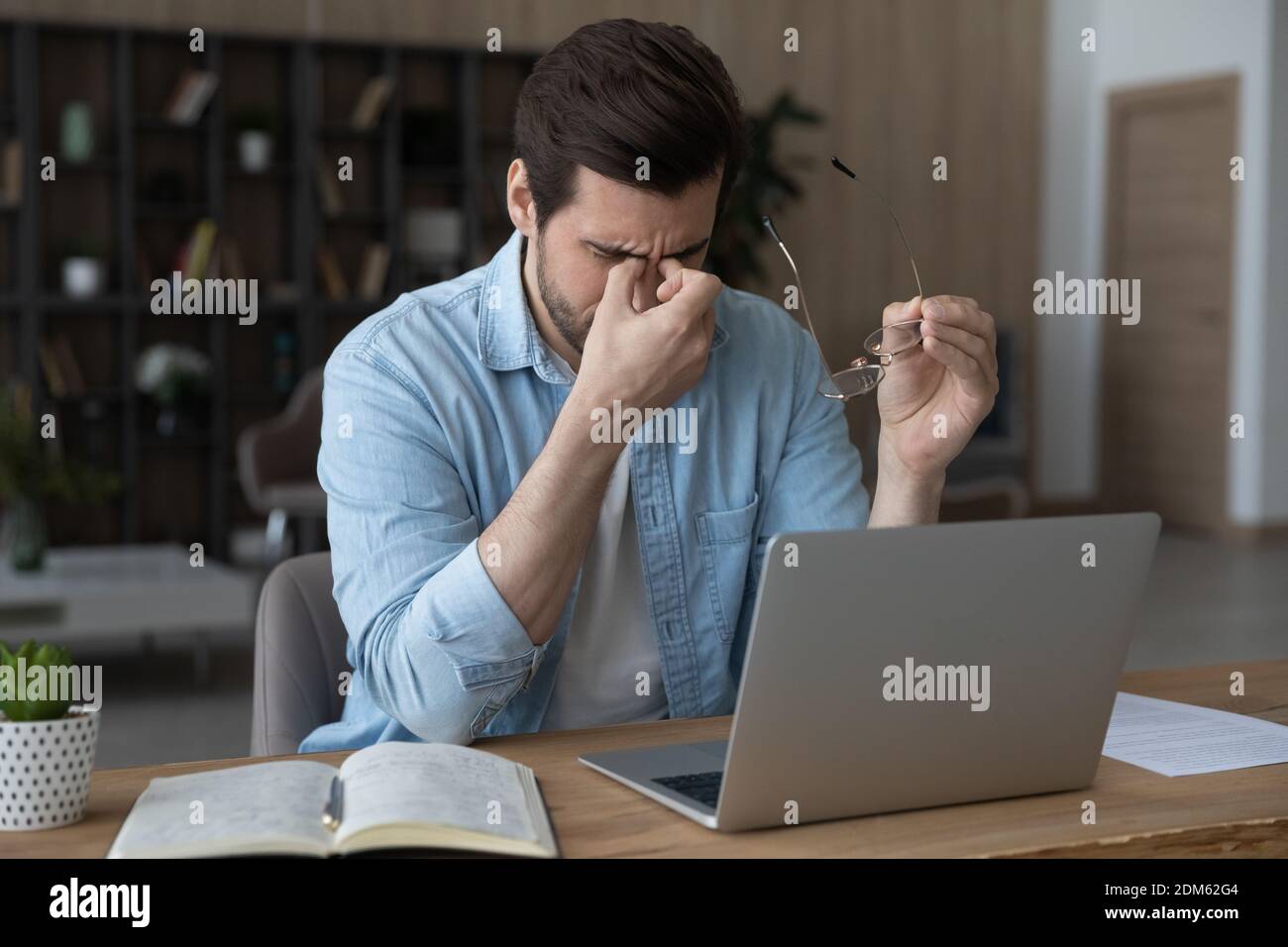 Exhausted man suffer from dizziness working on laptop Stock Photo - Alamy