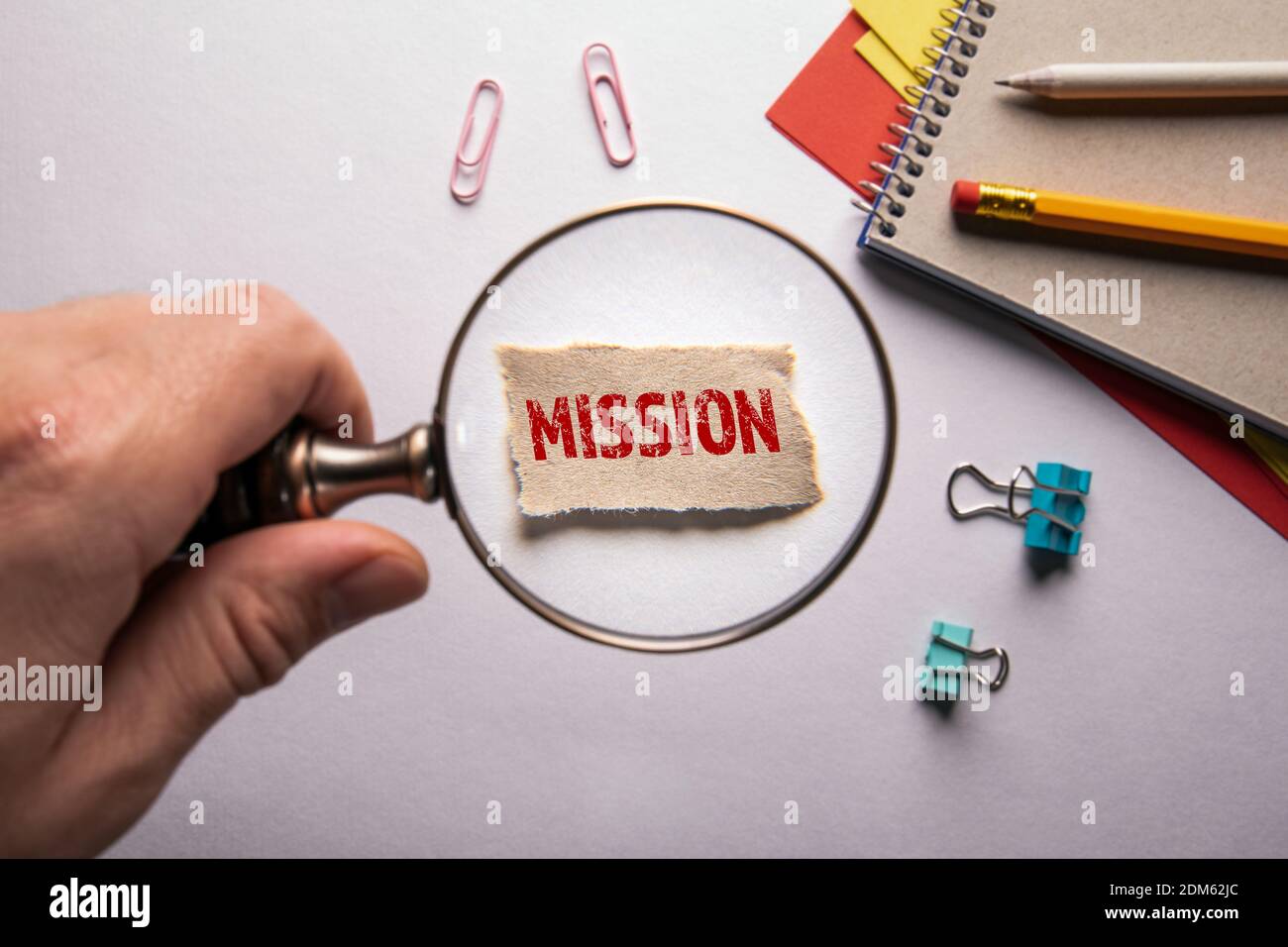 MISSION. Abstract business background. Man's hand, holding magnifying ...