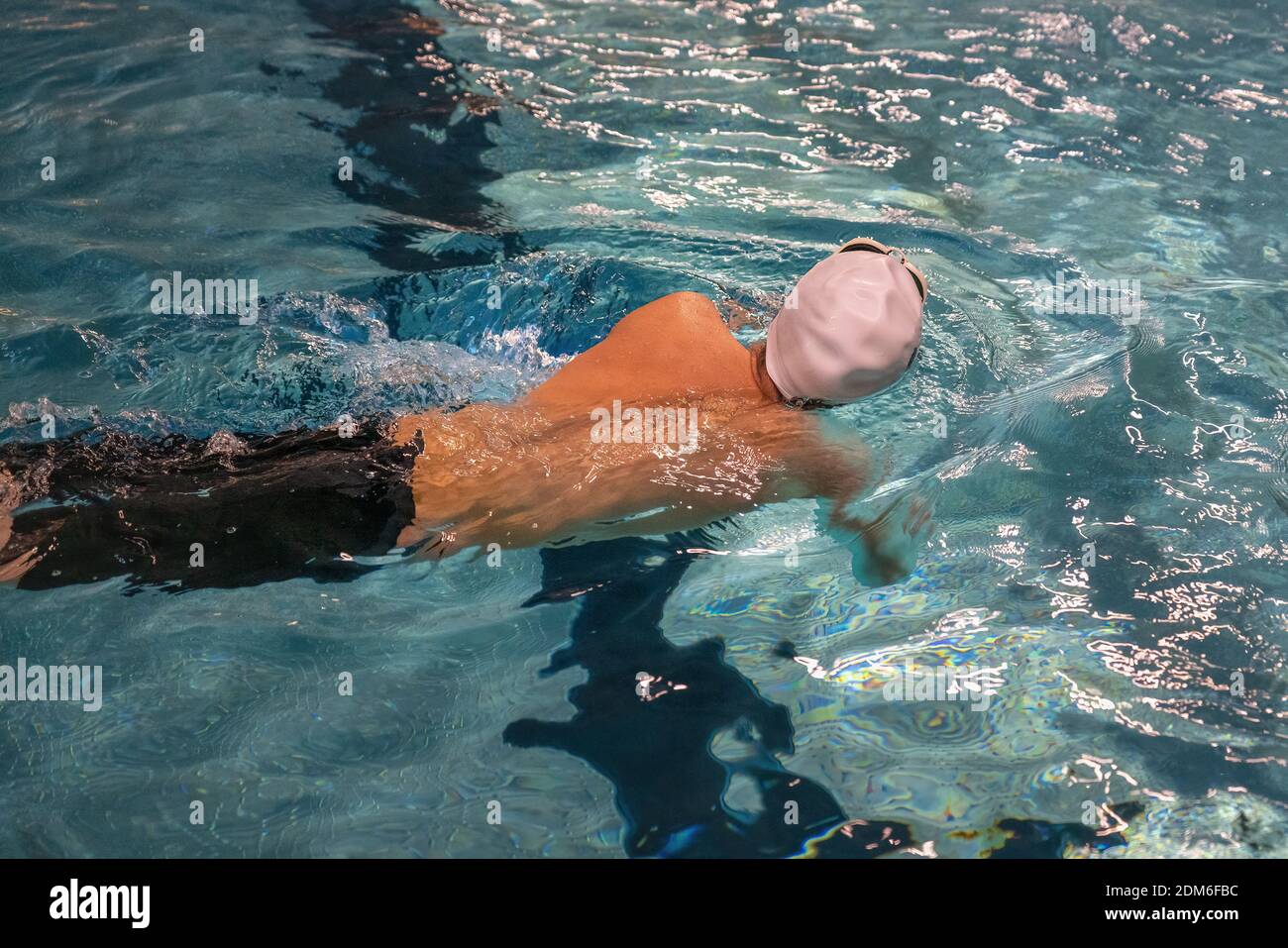 Young swimmer slowly swimming in swimming pool, back side view Stock ...