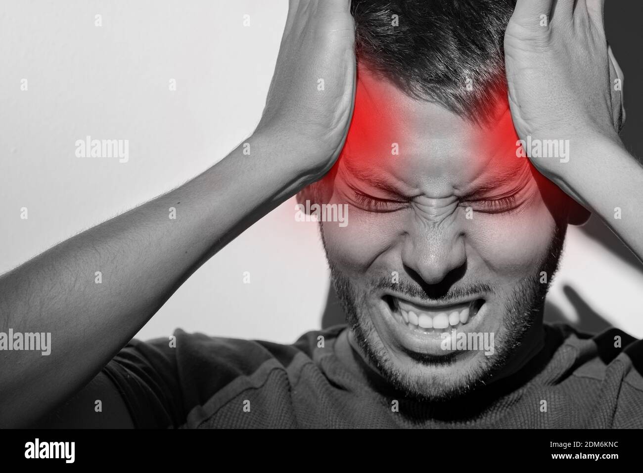 Portrait of young man suffering from painful migraine or strong tension ...