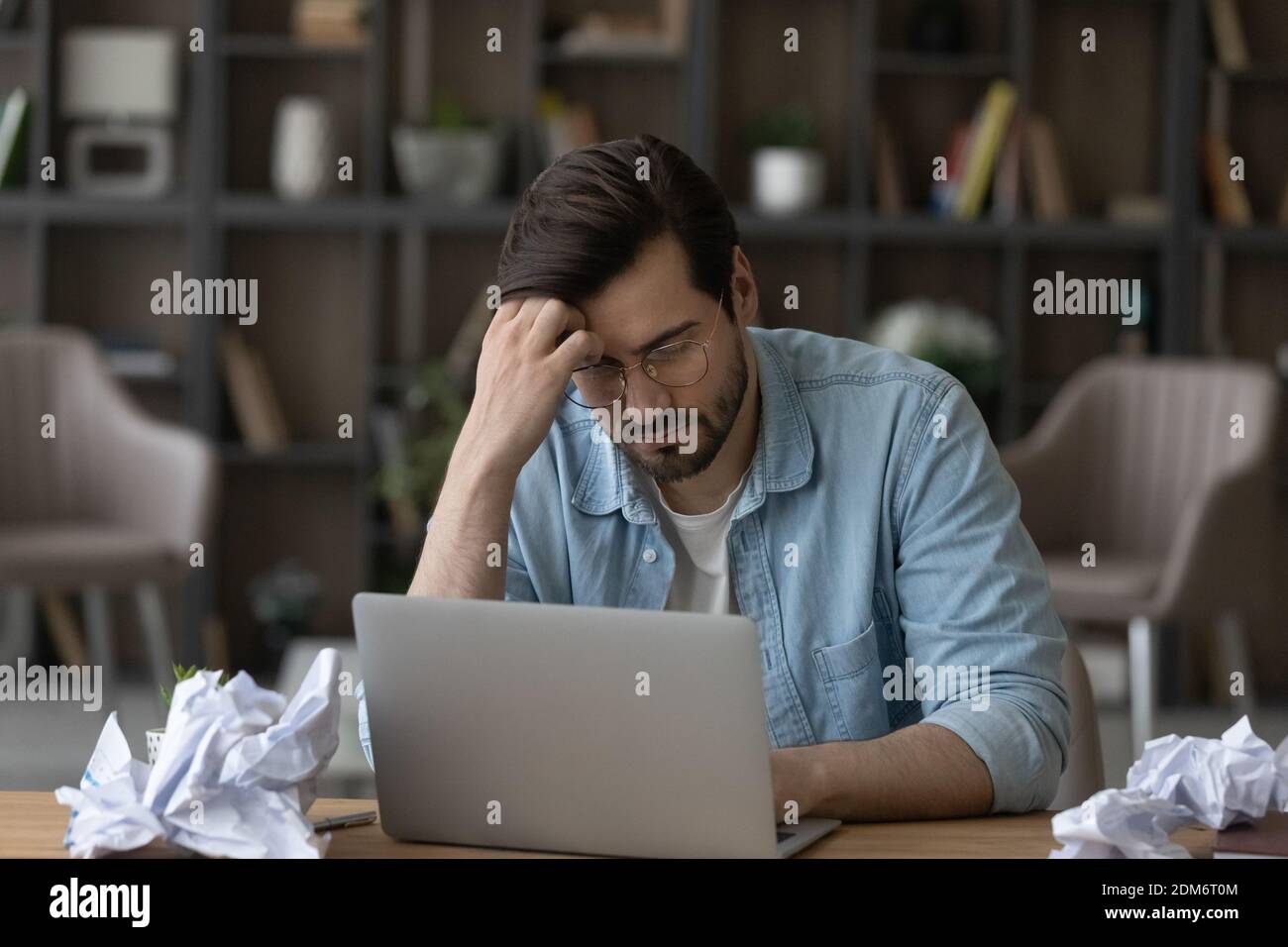 Tired young man overwhelmed with work at workplace Stock Photo - Alamy