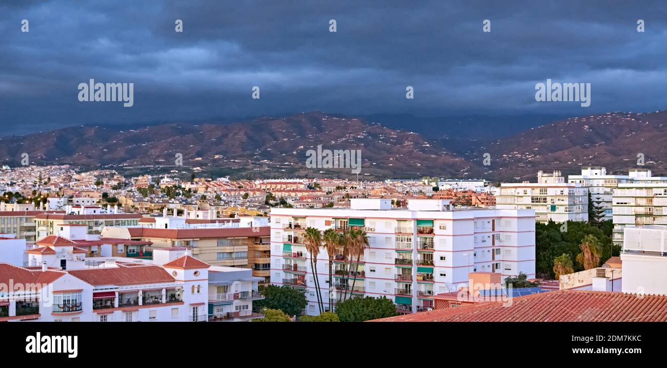 An aerial shot of a city with white blocky buildings under dark clou ...