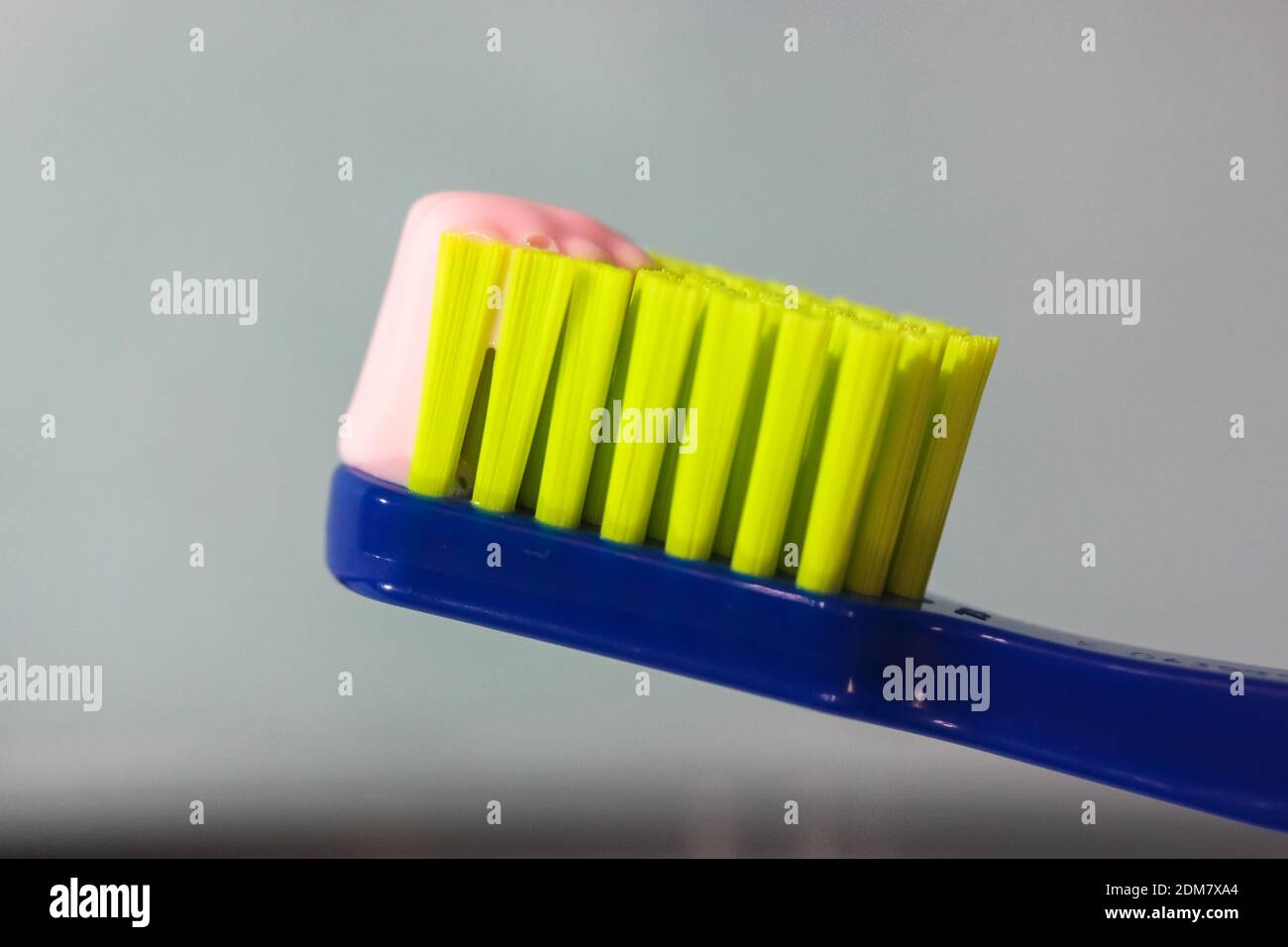 Blue toothbrush with green bristles close-up, pink toothpaste. Dental ...