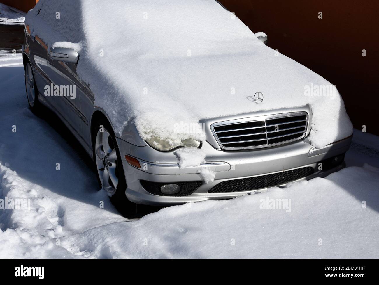 A Mercedes Benz automobile covered with snow parked in a parking lot in ...