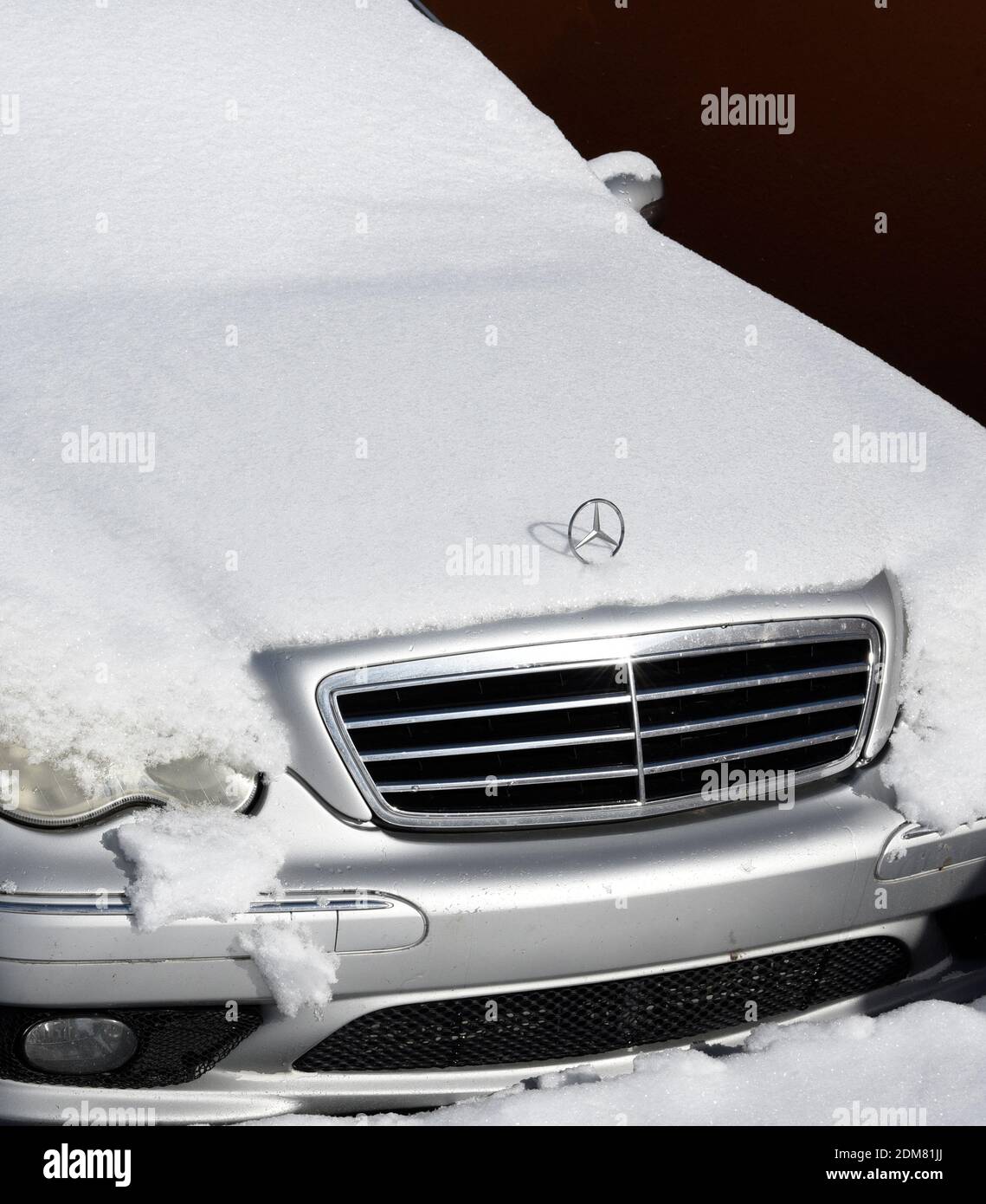 A Mercedes Benz automobile covered with snow parked in a parking lot in ...