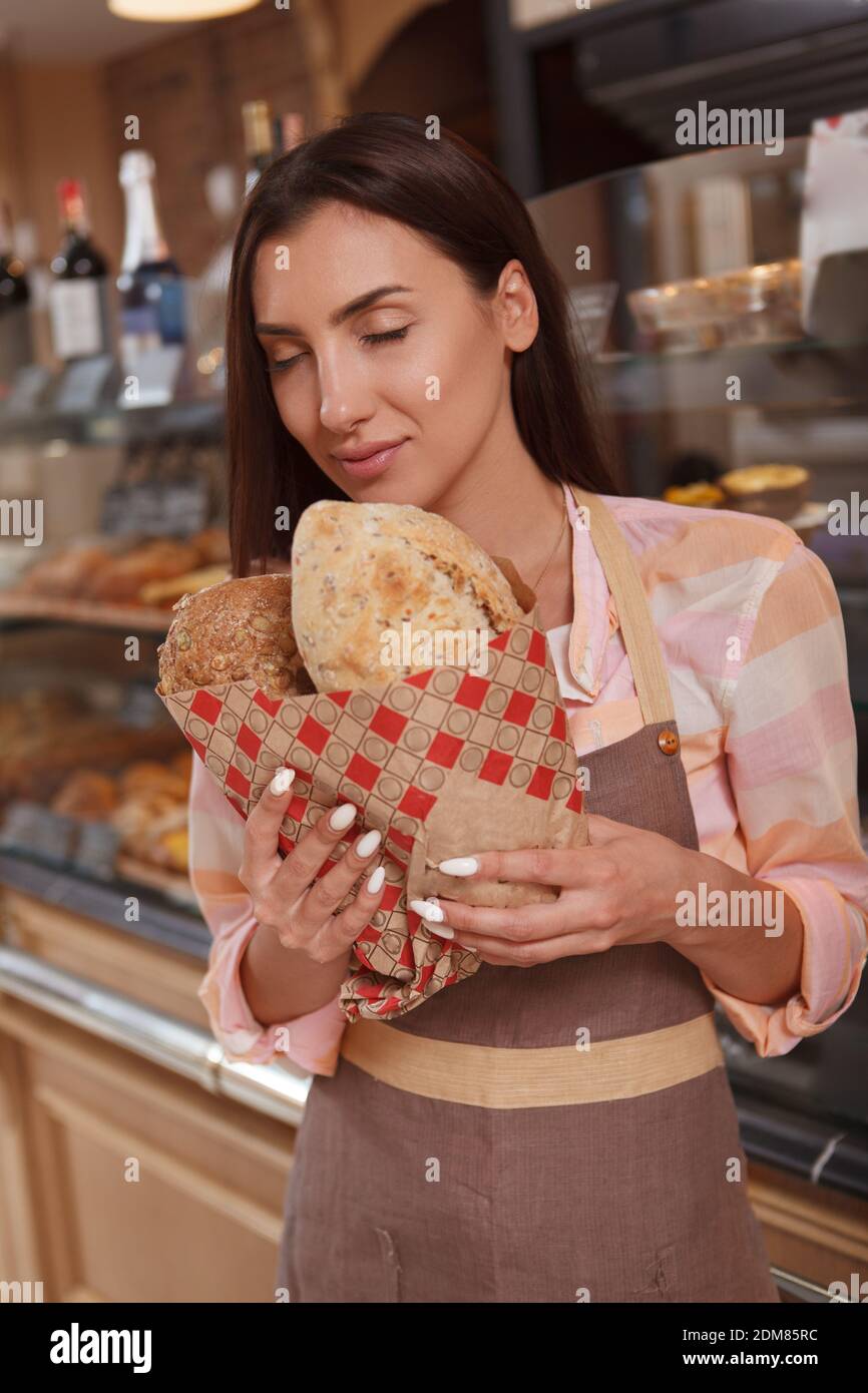 Vertical portrait of an attractive female baker smelling delicious ...