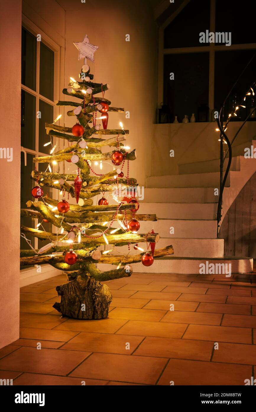 Rustic Christmas tree made of raw wood branches decorated with glowing ...