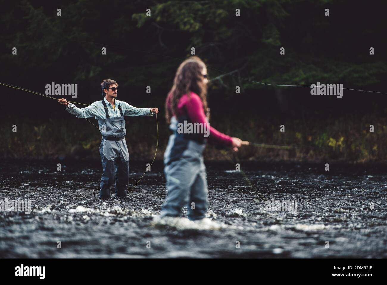 A man and a woman fish in a river with a dark background Stock Photo ...