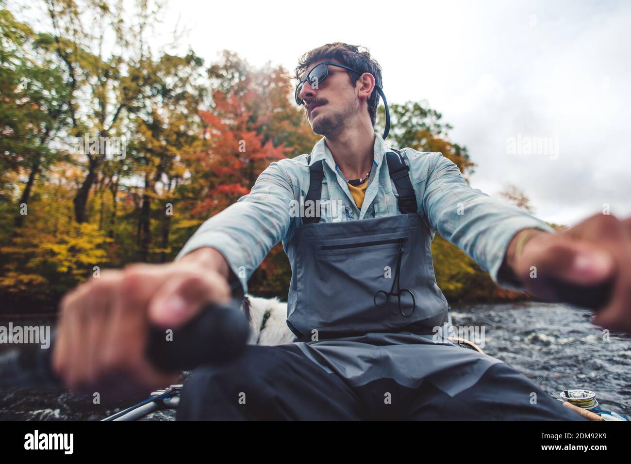 Fly fisherman rowing boat down river in fall foliage season Stock Photo ...