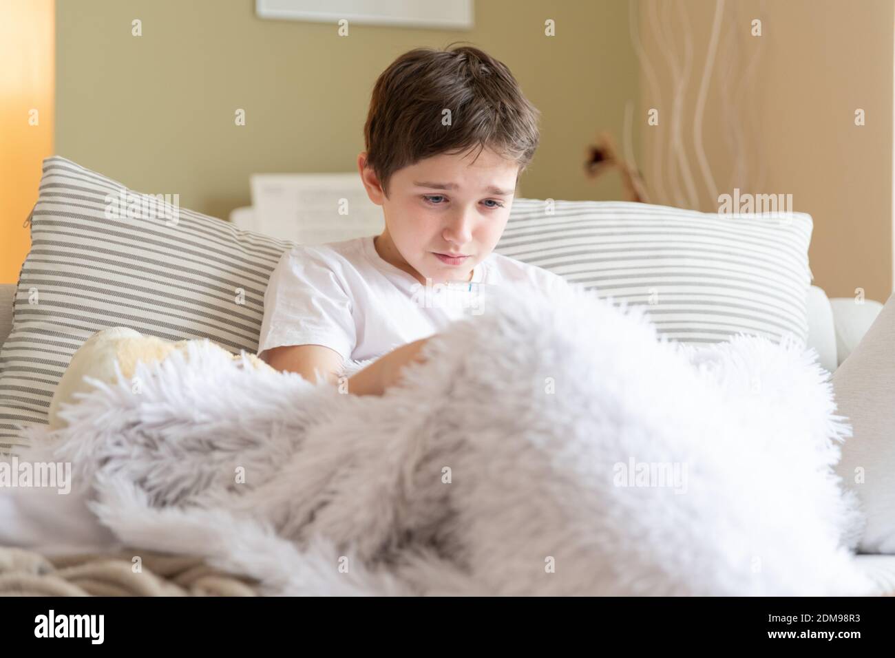 The sick boy is sitting under the blanket feeling unwell Stock Photo ...