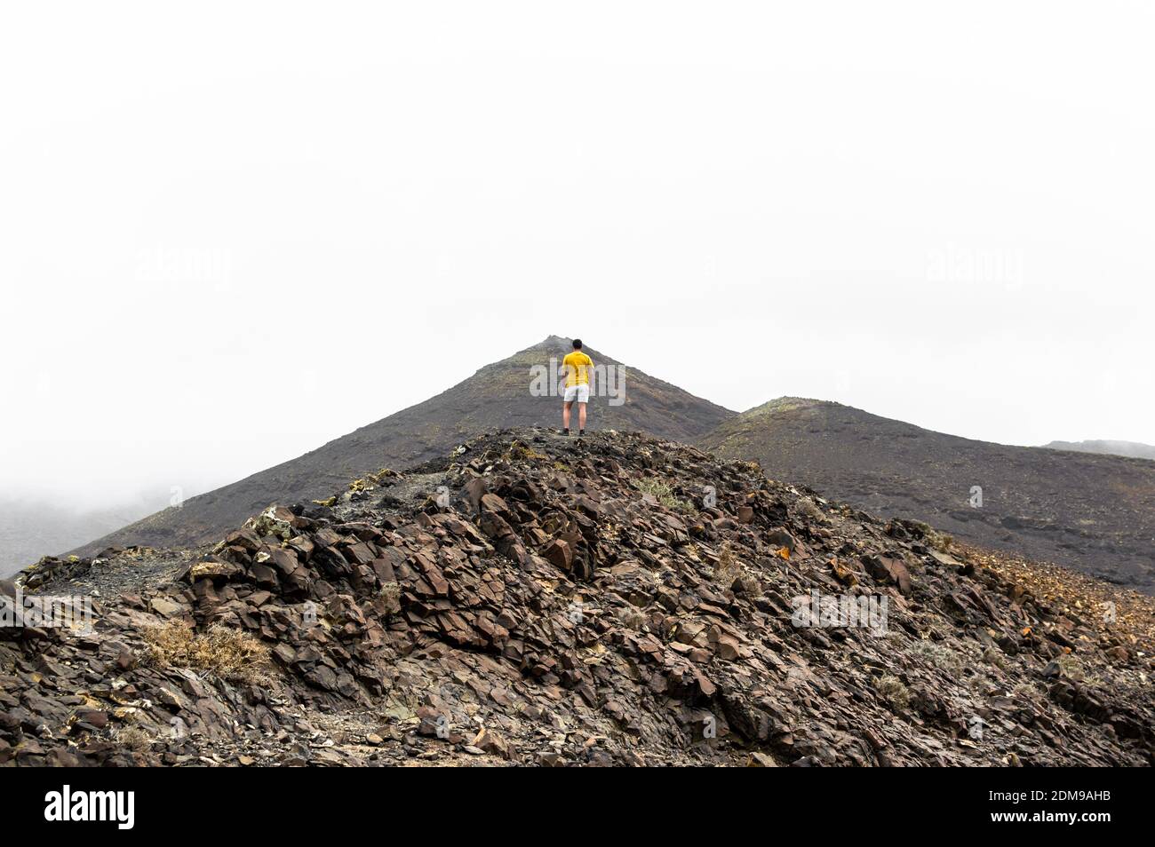 Back view of a young mountain climber standing on top of a mountain ...
