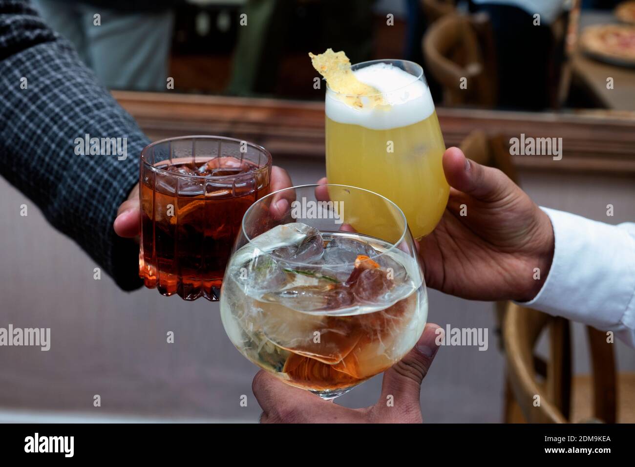 Three friends celebrating with cocktails on their hands Stock Photo - Alamy