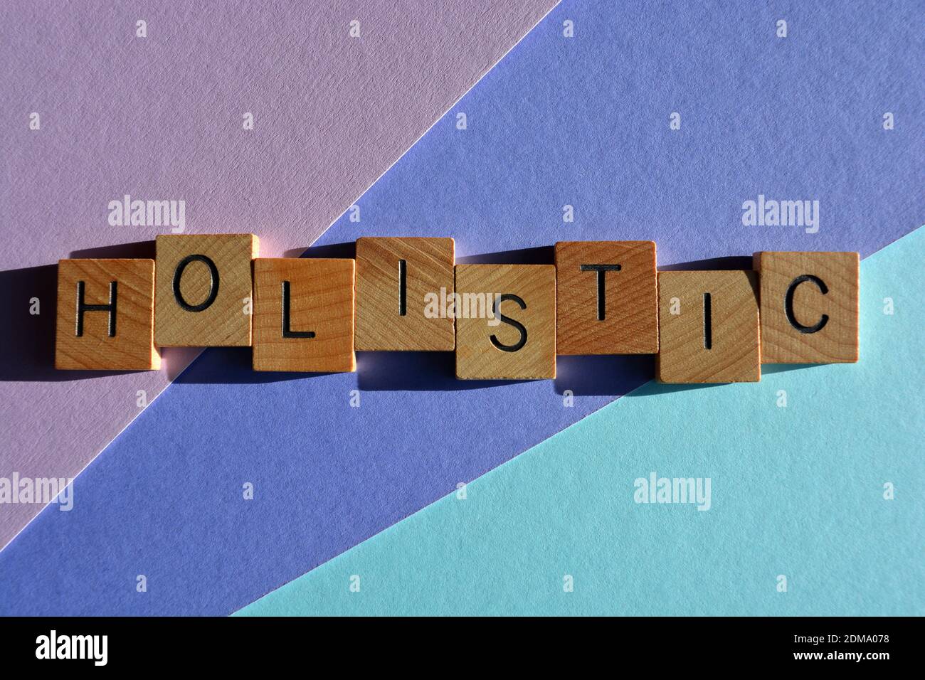 Holistic, word in wooden alphabet letters isolated on pastel coloured ...