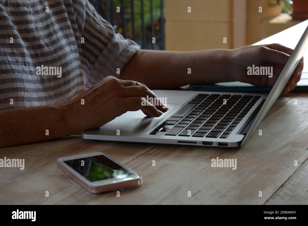 Mid section viewpoint, woman seated using a laptop computer, hand on ...