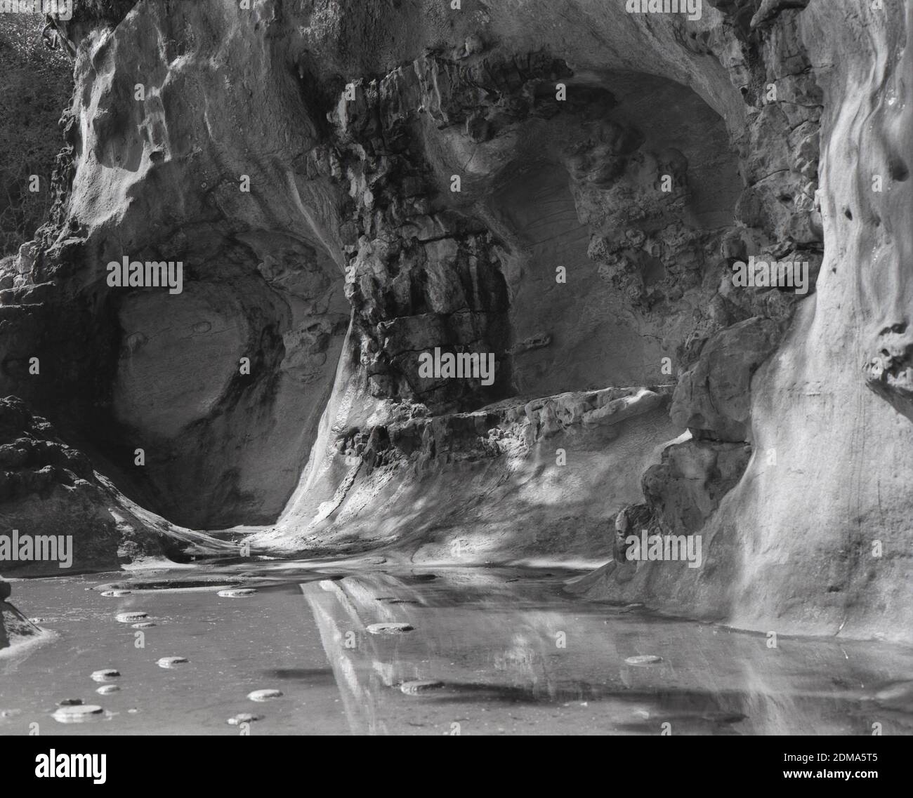 rock face on beach with water and reflection Stock Photo - Alamy