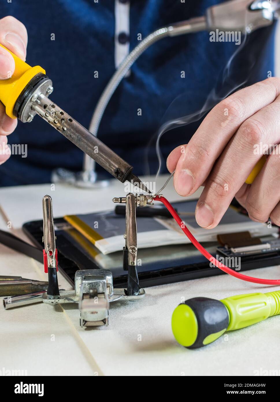 A vertical shot of male hands soldering a cable to an electronic device ...
