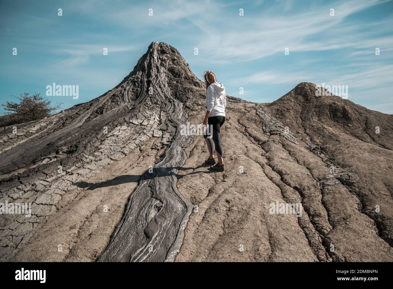 Young girl conquering a mud volcano's peak wearing sportswear, Romania ...