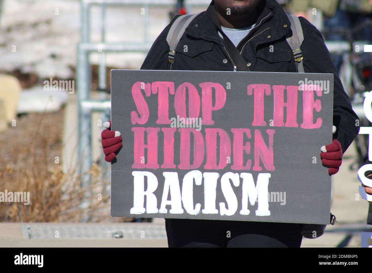 A view of college student protest with "STOP THE HIDDEN RACISM" placard ...