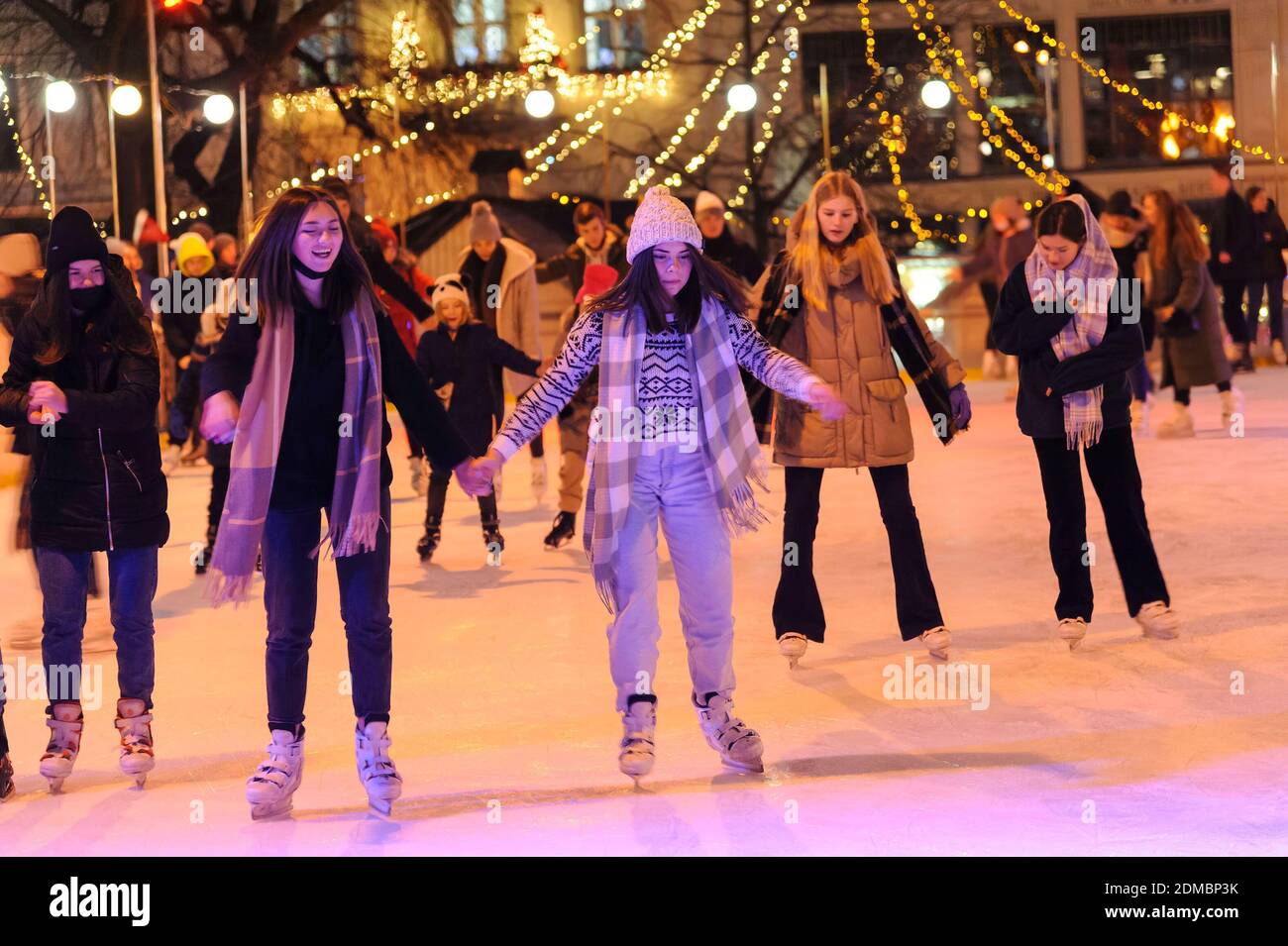 People ice-skating with Christmas lights in the background in downtown ...