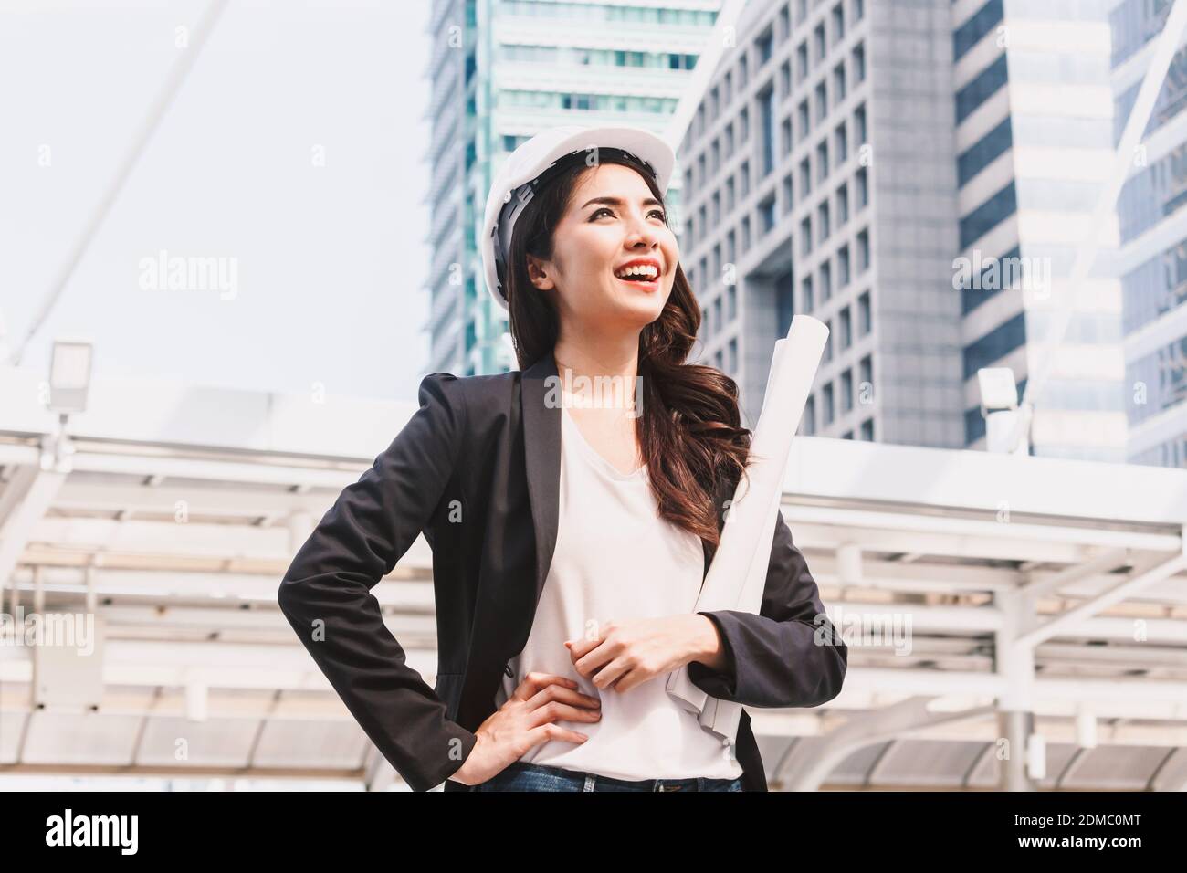 Beautiful woman engineer holding blueprint on city background Stock ...