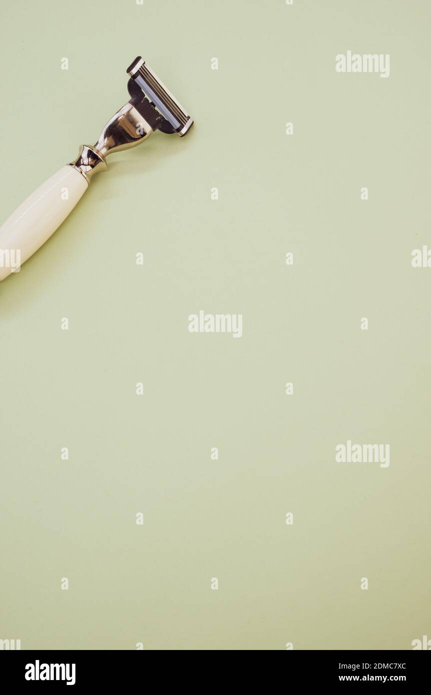 A vertical shot of a beige and black razor isolated on a green ...