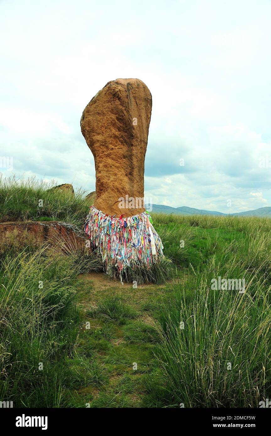 An ancient sacred stone monument with ritual ribbons stands in the ...
