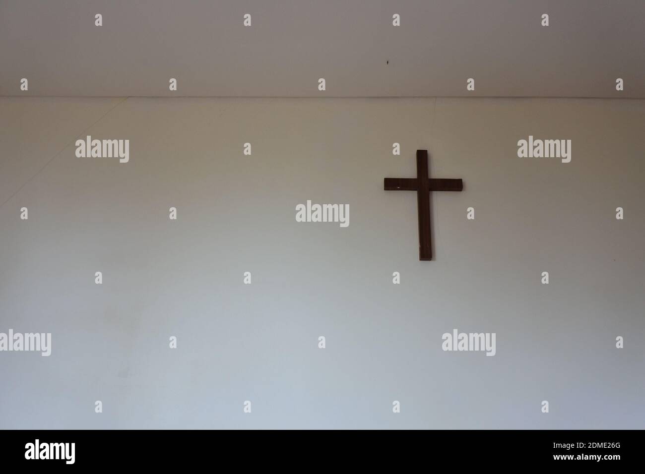 A simple wooden cross hangingon a white wall in a room Stock Photo - Alamy