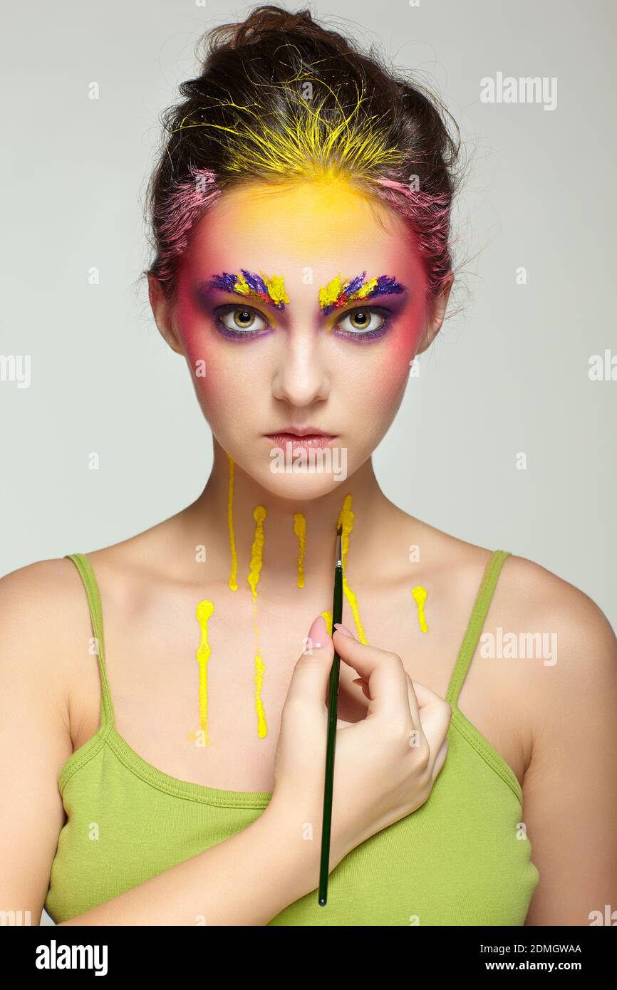 Female portrait with unusual face and body art make-up. Paint on brows ...