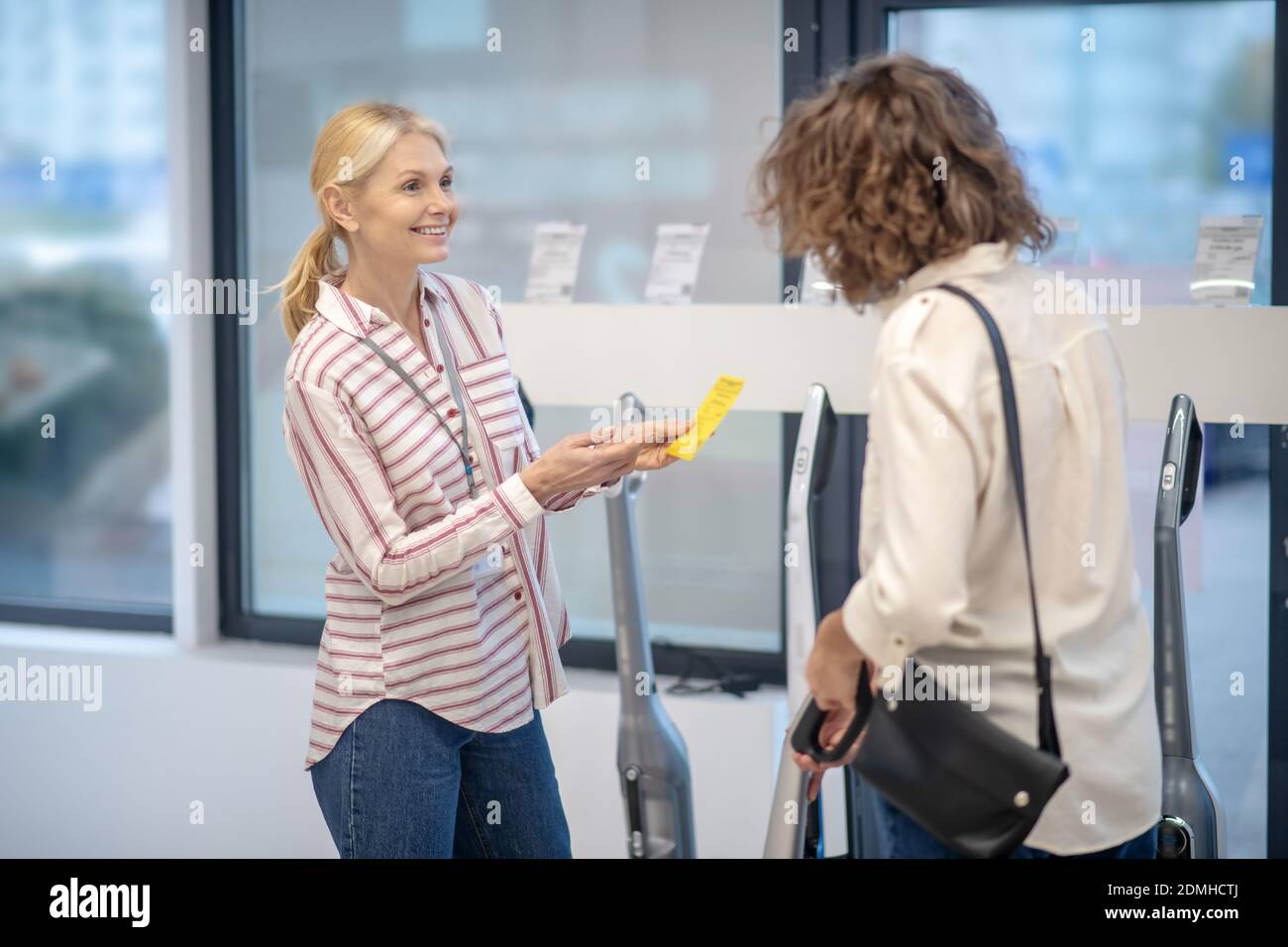 Female sales assistant in striped shirt showing new devices to the ...