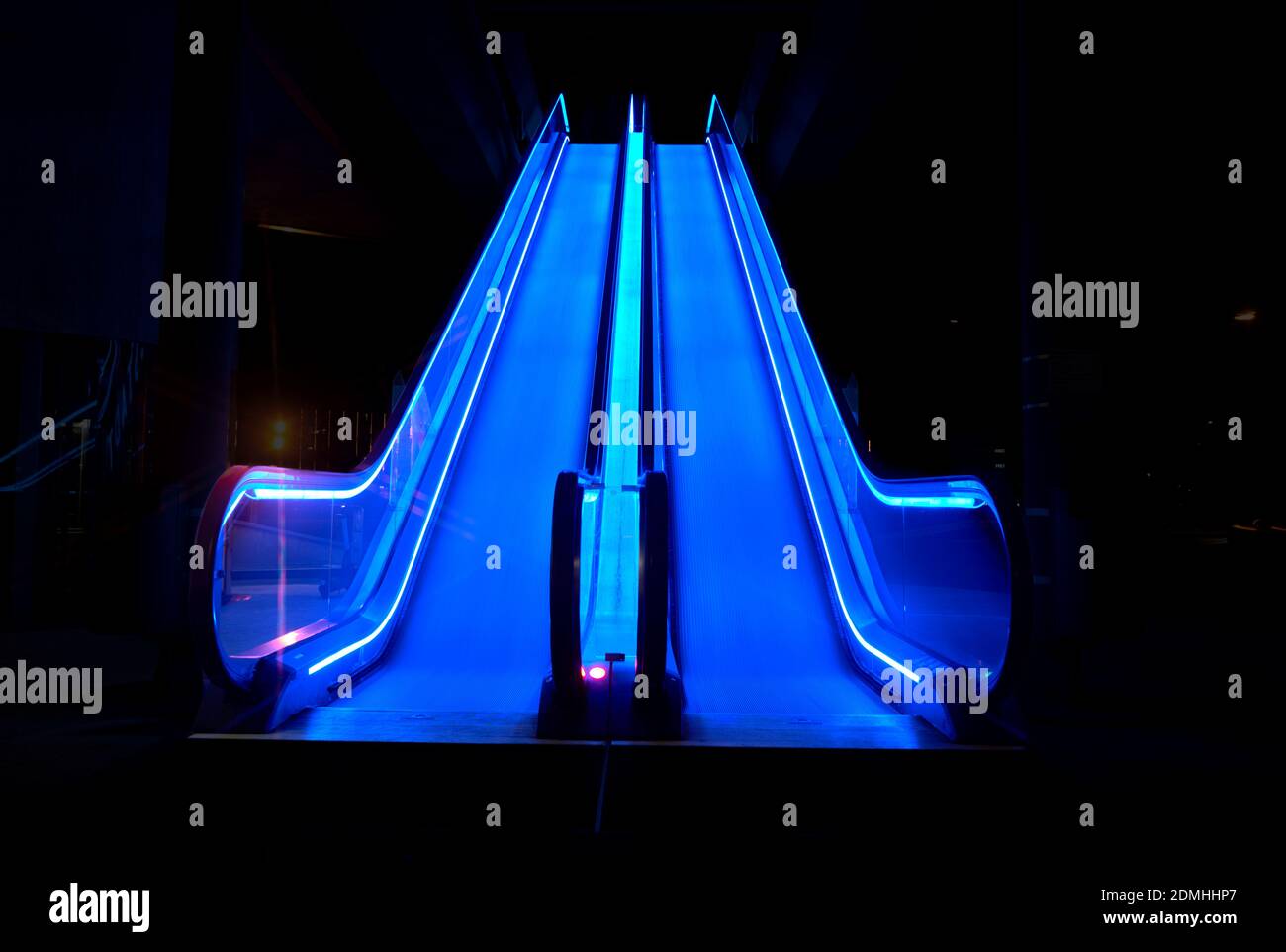 Blue illuminated escalator at night with intentional motion blur of the ...
