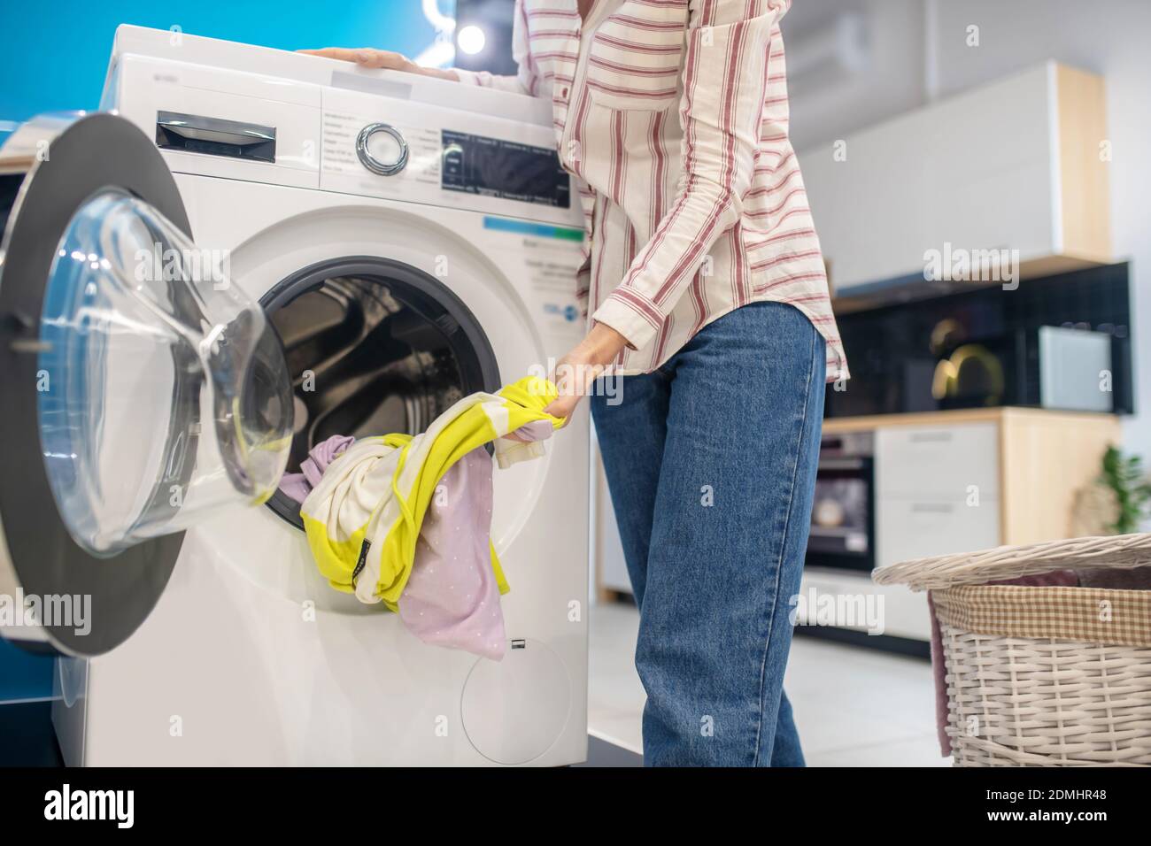 Blonde woman taking clothes from washing machine Stock Photo - Alamy