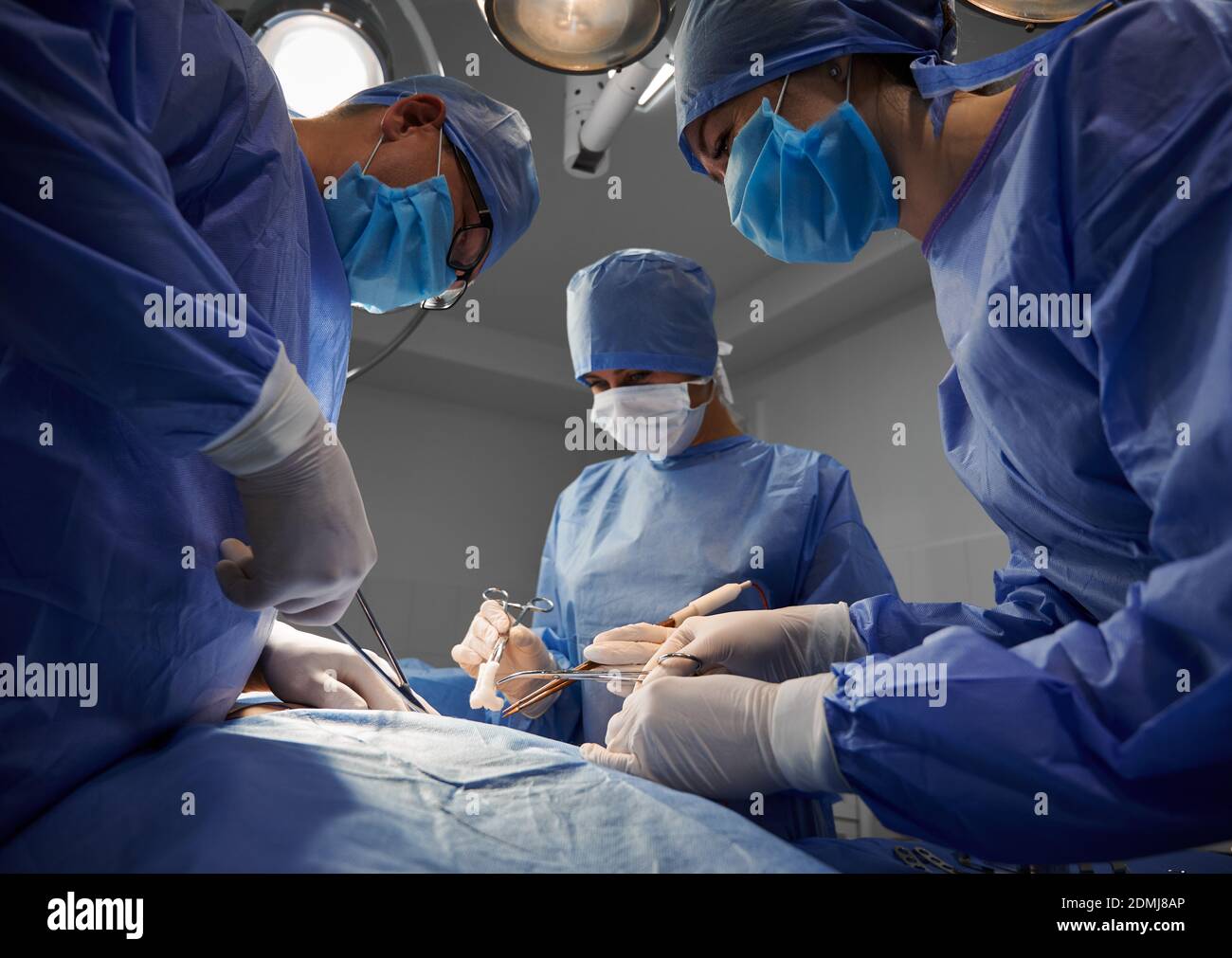 Surgical team in blue medical suits using medical instruments and ...
