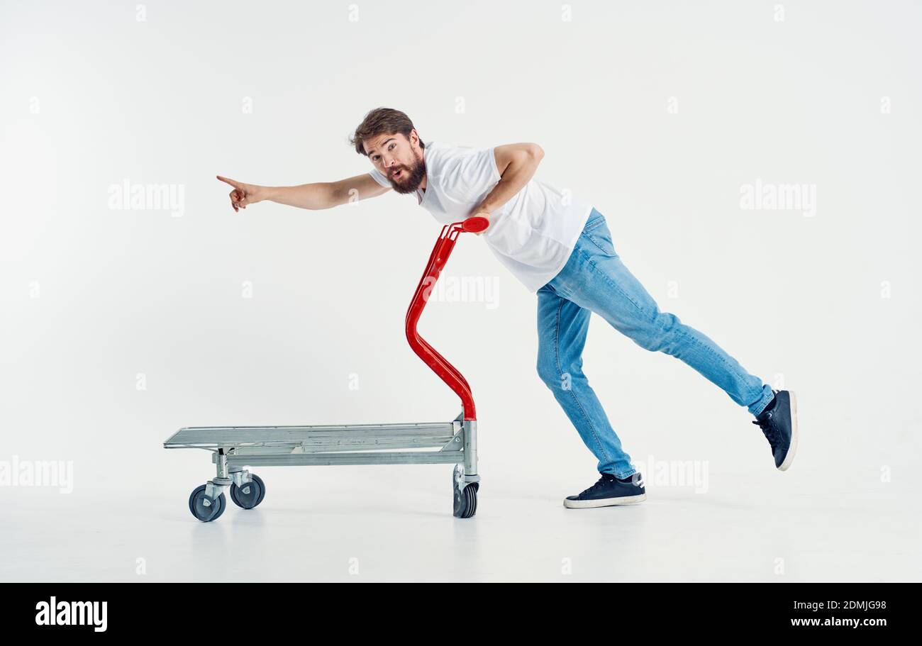 cargo trolley man in jeans and sneakers light background work ...