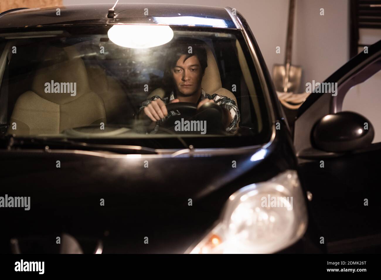 tired taxi driver parked the car in the garage, opened the door, sits ...