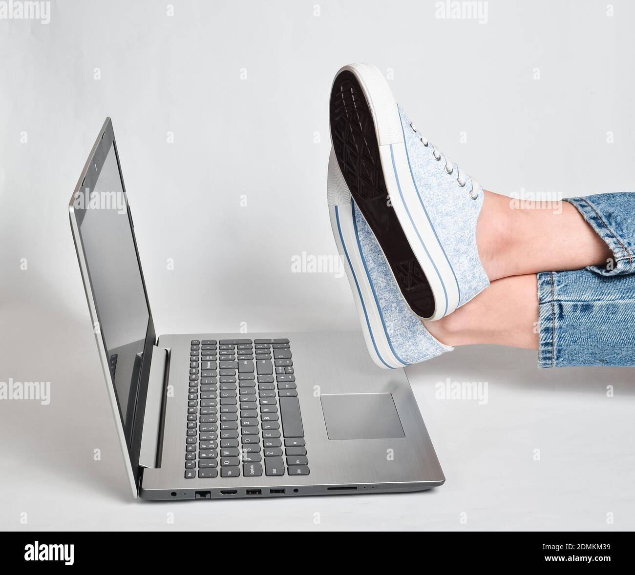 Female legs in jeans and sneakers are lying down foot on the laptop on ...