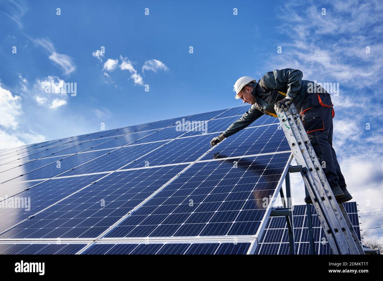 Male electrician in white safety helmet standing on ladder and mounting ...