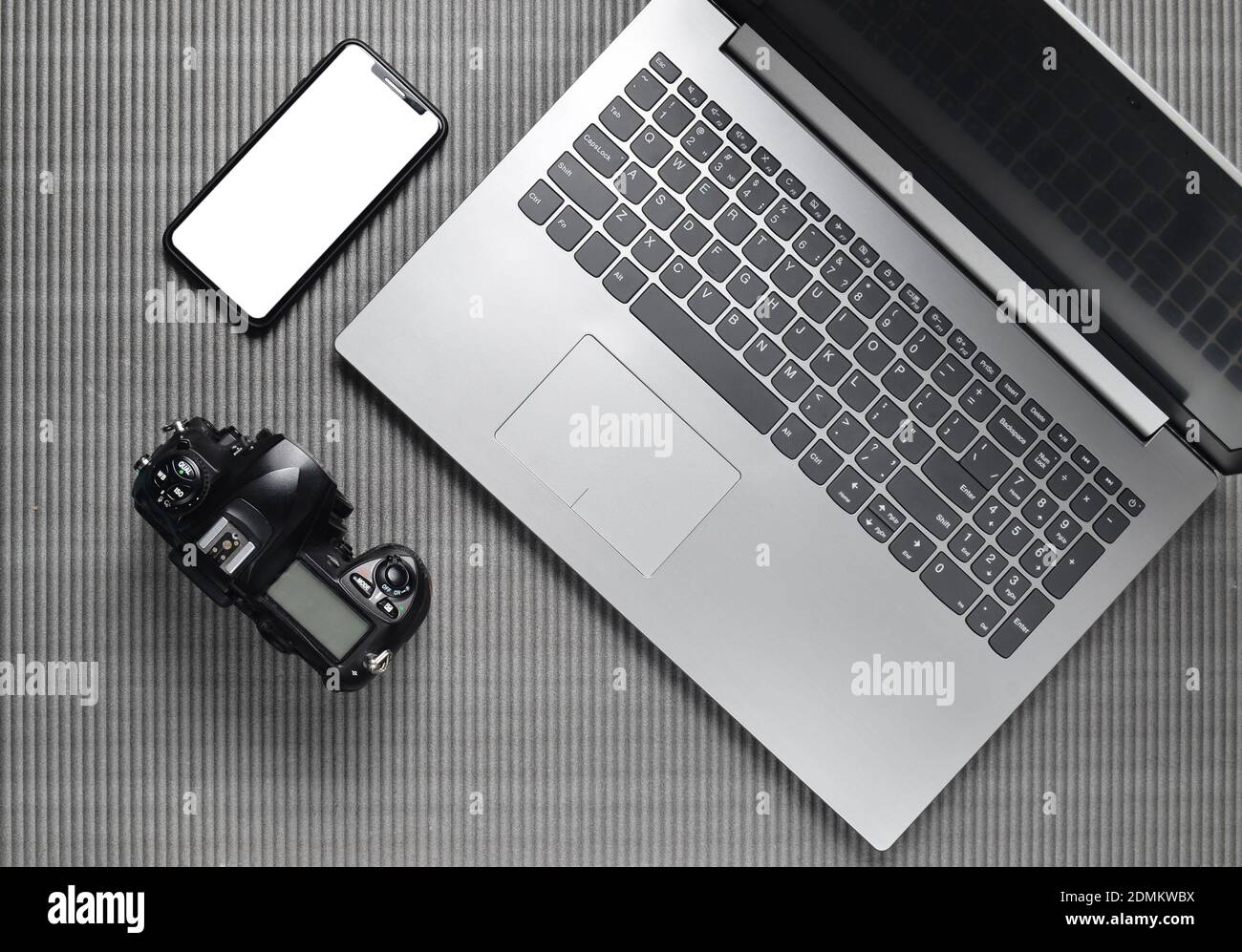 Laptop, frameless phone with white screen, camera on a gray texture ...