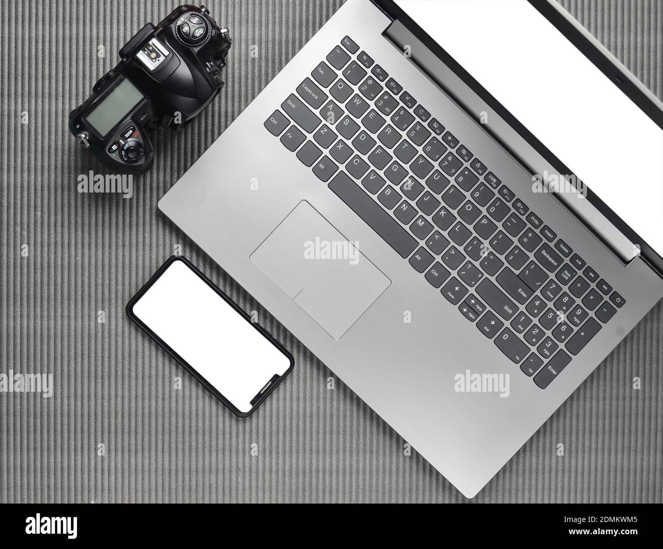 Laptop, frameless phone with white screen, camera on a gray texture ...
