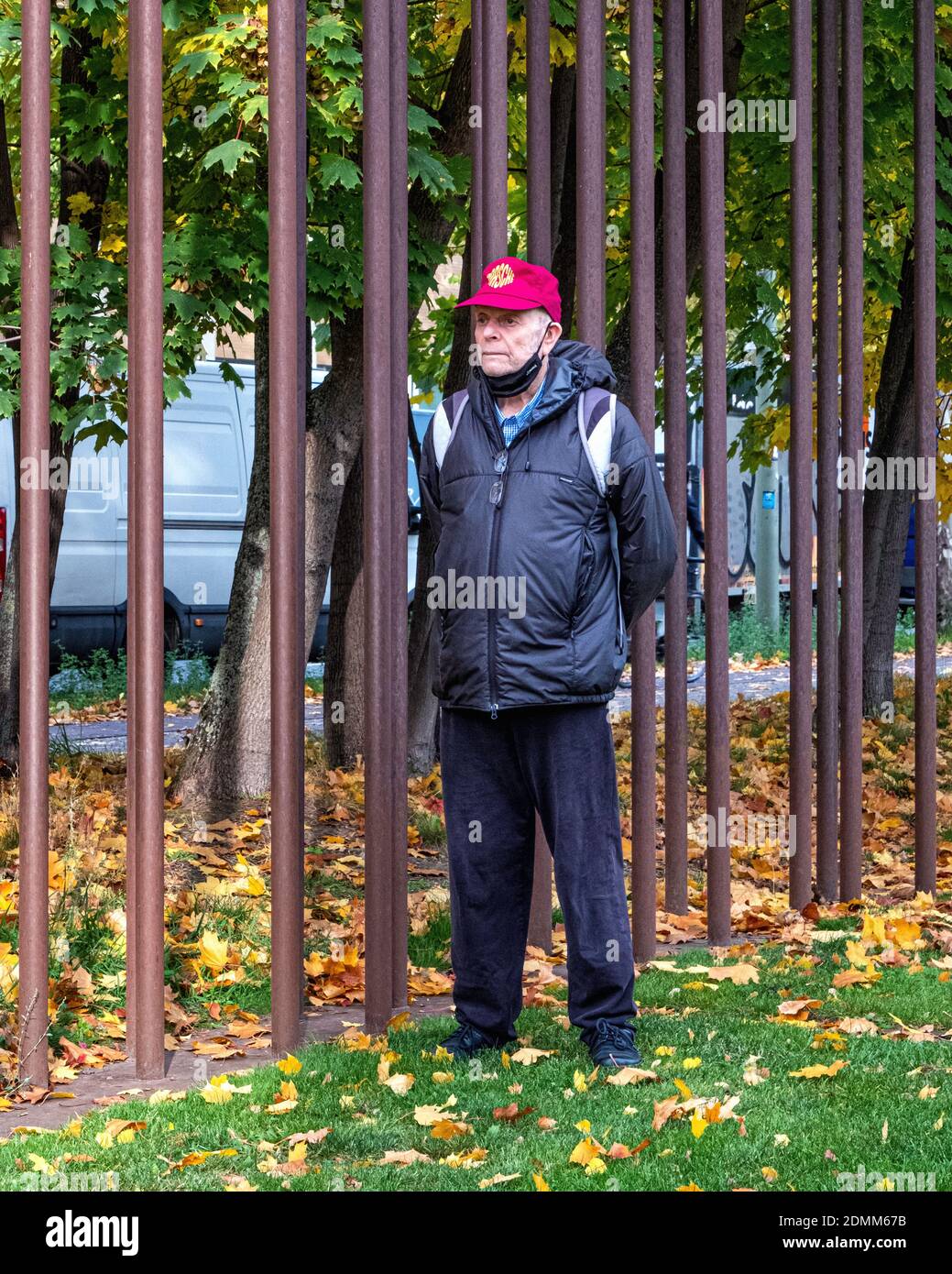 Senior man standing next to rusty poles that represent Berlin Wall at ...