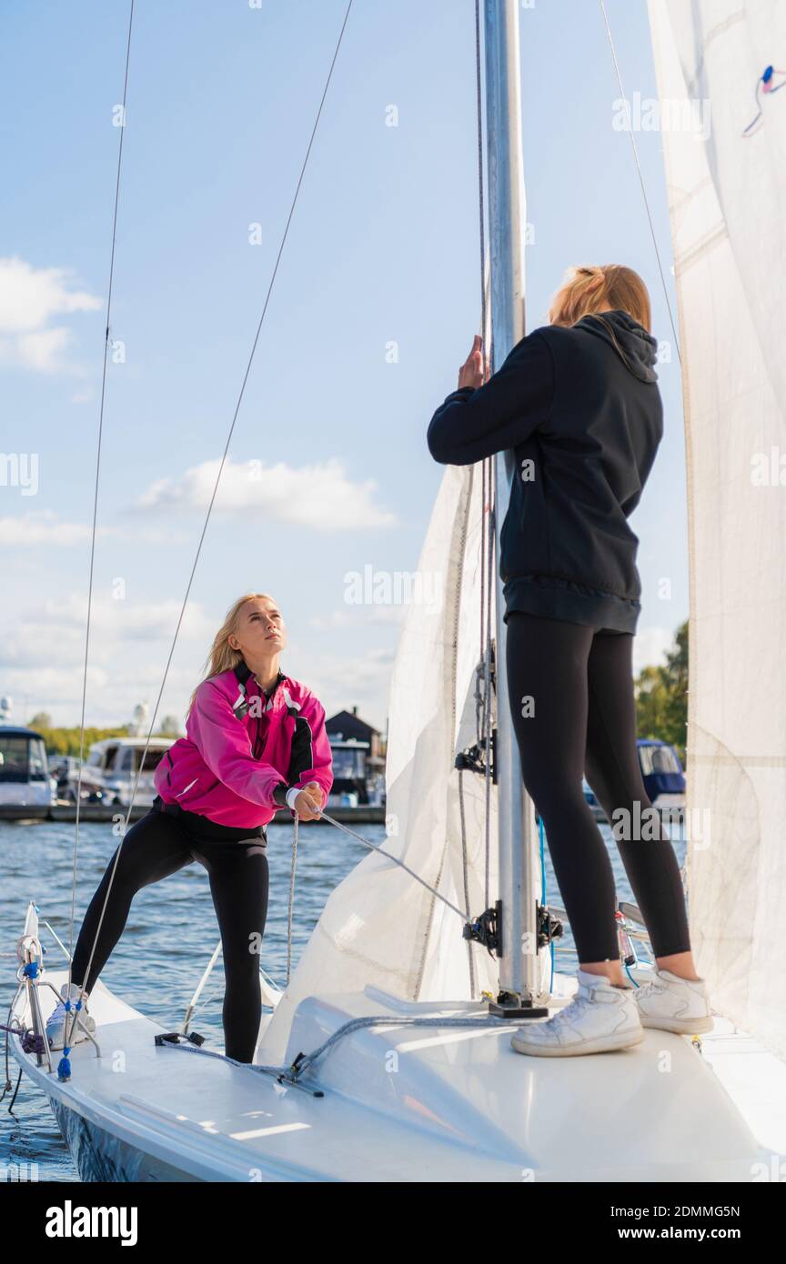 Before the competition on sailing boats two cute girls athletes equip ...
