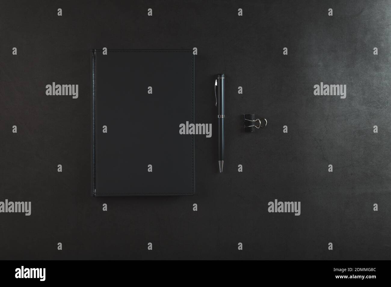 Office desk with black notepad and pen on black background. Top view ...